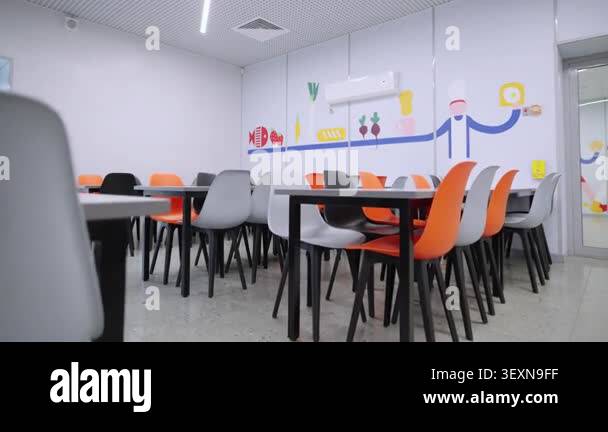 School canteen features neat rows of tables paired with vibrant chairs ...