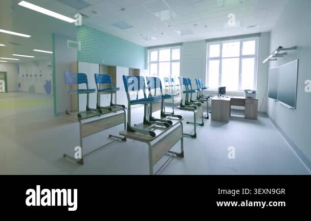 Chairs stand on top of wooden desks in empty classroom. Clean interior ...