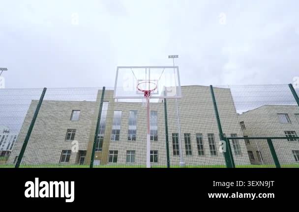 Transparent basketball backboard with red rim stands against cloudy sky ...
