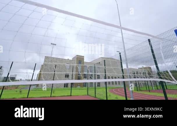 Volleyball net stretches across foreground of outdoor court. Modern ...