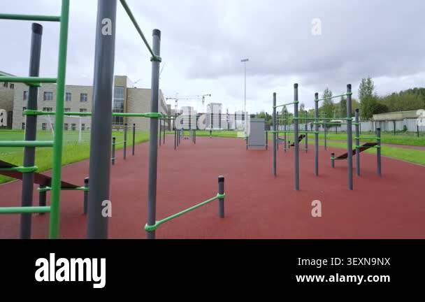 Outdoor workout area features bars and pull-up stations on red surface ...