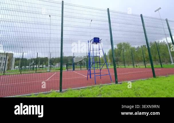 Referee chair stands beside volleyball net on red court. High metal ...