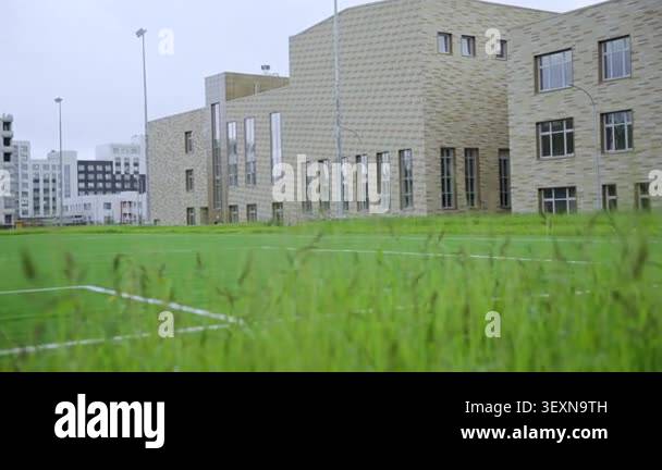 Large modern school building with tan brick facade. Professional green ...