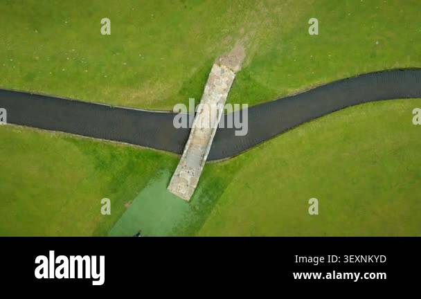Solitary person walking over an old stone bridge crossing a stream in a ...