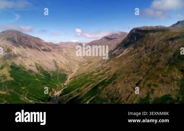 Aerial view flying through a steep mountain valley with a river and ...