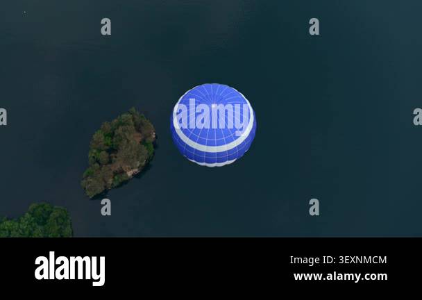 Top down aerial view of a hot air balloon floating above a serene lake ...