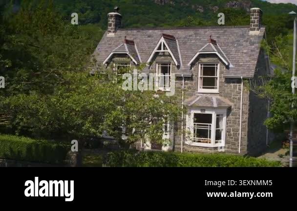 Picturesque stone house with a slate roof nestled amongst lush green ...