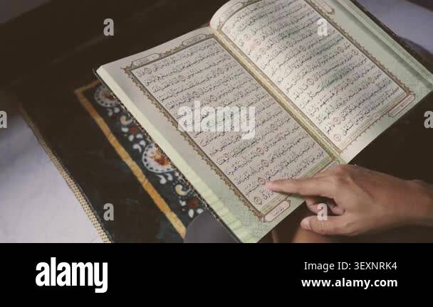 Close-up of a Muslim reading the Holy Quran on a prayer mat during ...