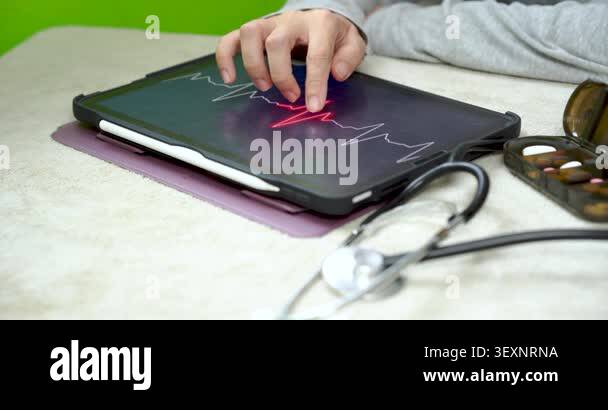 Close-up of a person touching an ECG waveform on a digital tablet ...