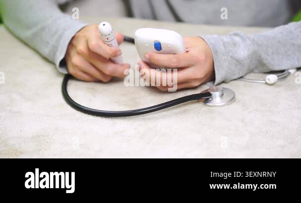 Close-up of a person holding a fingertip pulse oximeter during a home ...