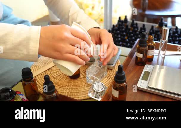 Close-up of hands filling a perfume bottle during handmade fragrance ...