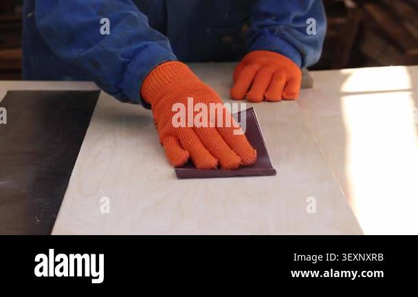 he process of manual sanding of light plywood or wooden board. A person ...