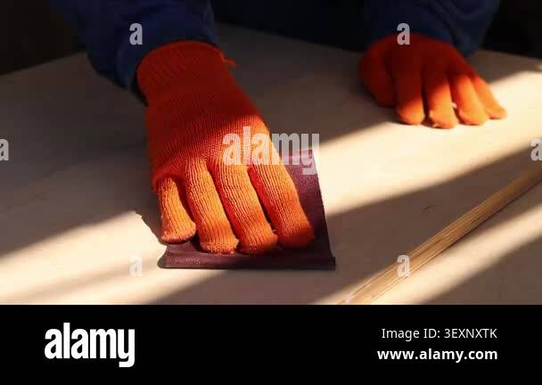 he process of manual sanding of light plywood or wooden board. A person ...