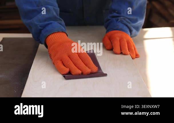 he process of manual sanding of light plywood or wooden board. A person ...