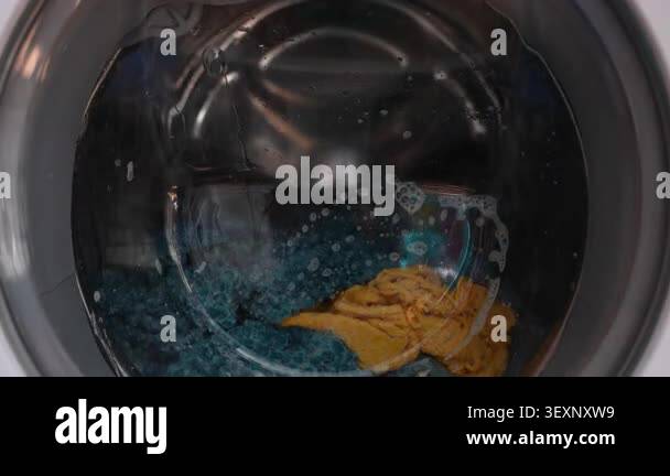 Clothing and soapy water spin around in machine. Washing machine door ...
