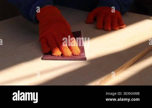 he process of manual sanding of light plywood or wooden board. A person ...
