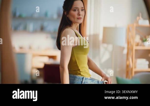 Woman frustrated loose-fitting jeans looking home mirror closeup. Slim ...