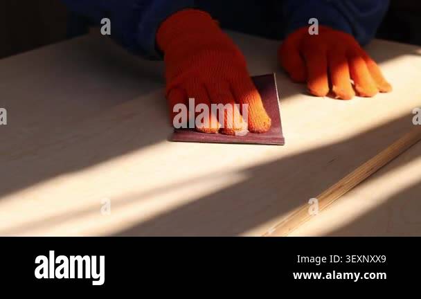 he process of manual sanding of light plywood or wooden board. A person ...