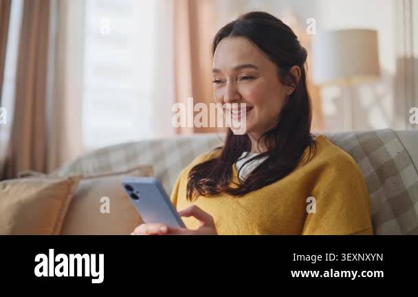 Relaxed girl using cellphone sitting living room at relaxing day home ...