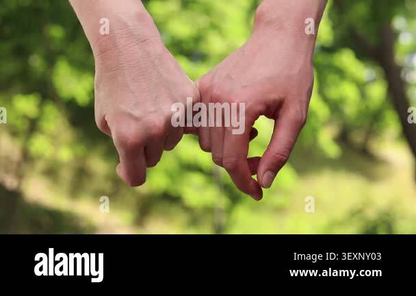 Two women holding hands. Close-up of two women's hands holding pinkies ...