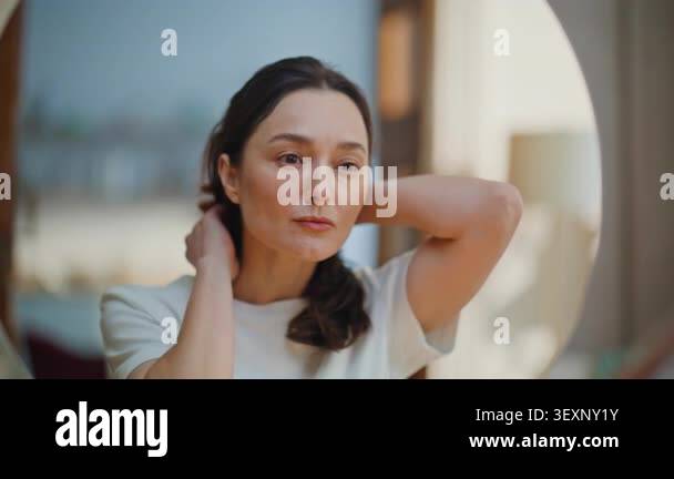 Woman examining face in mirror searching wrinkles aging signs closeup ...