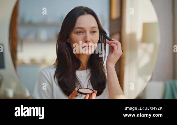 Girl using makeup brush applying powder looking home mirror closeup ...
