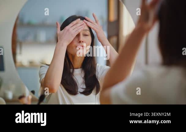 Lady applying anti-age cream on face performing morning beauty routine ...