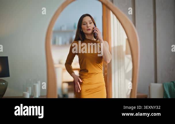 Beautiful brunette adjusting gorgeous gown standing mirror talking ...