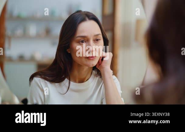 Sad woman looking mirror thoughtfully at quiet home setting closeup ...