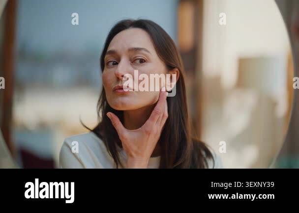 Lady inspecting face reflection gently touching smooth skin closeup ...
