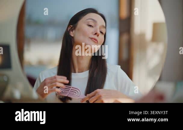 Woman brushing long hair at calm morning routine looking apartment ...