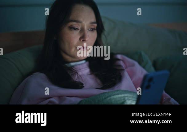 Lonely woman lying blanket bed browsing social media phone closeup ...