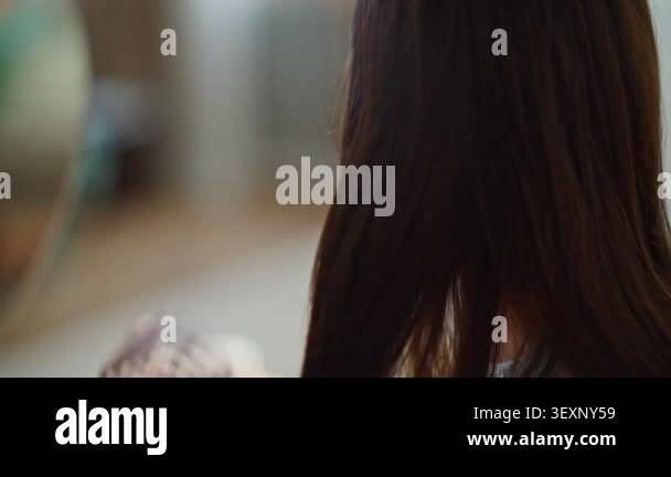 Smiling lady styling hair using hairbrush checking appearance in home ...