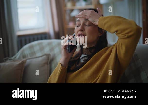 Frustrated lady speaking mobile phone sitting sofa apartment alone ...