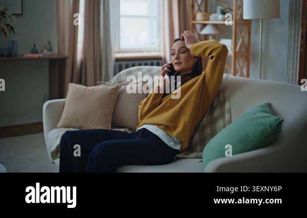 Nervous lady speaking smartphone sitting domestic living room. Stressed ...