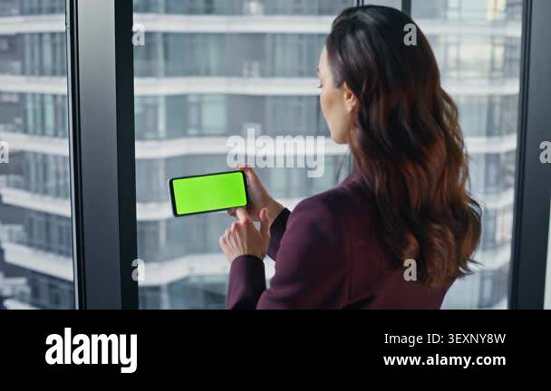 Lady employee touching greenscreen cellphone opening email in cityscape ...
