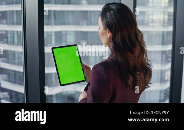 Entrepreneur browsing chromakey tablet data at business center window ...