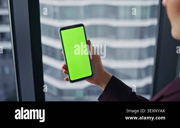 Manager hand holding greenscreen cellphone standing at window city view ...
