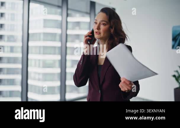 Luxurious woman speaking mobile phone walking on office corridor ...