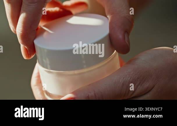 Woman hands unscrewing cosmetic cream container in soft morning ...