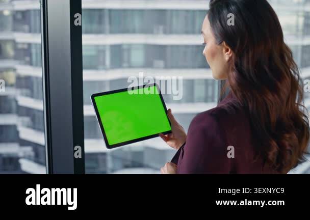 Successful lady holding mockup tablet standing by window office center ...