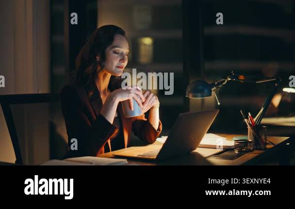 Late worker drinking coffee sitting modern office workspace in lamp ...
