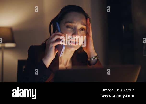 Nervous brunette talking smartphone sitting dark remote workplace ...