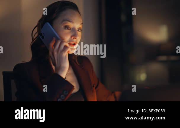 Friendly businesswoman calling telephone sitting office at night ...
