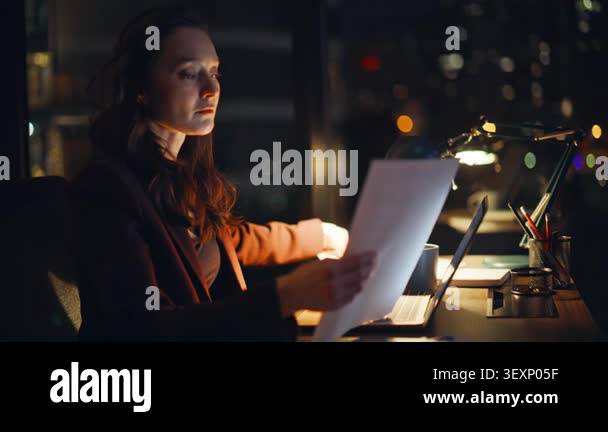 Overloaded employee staying late flipping papers in dim corporate room ...
