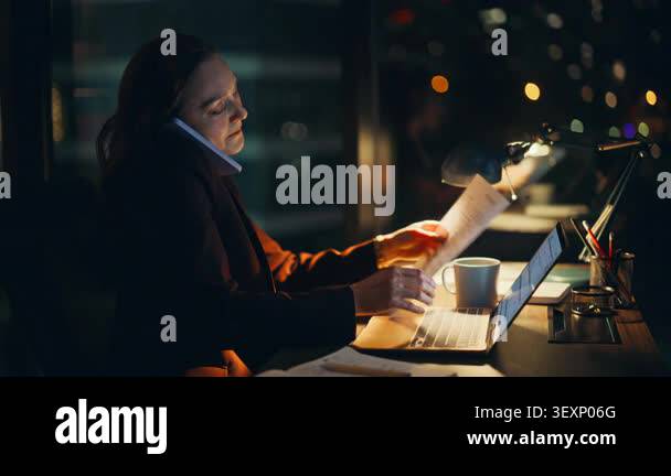 Night manager speaking cellphone sitting workplace with laptop ...