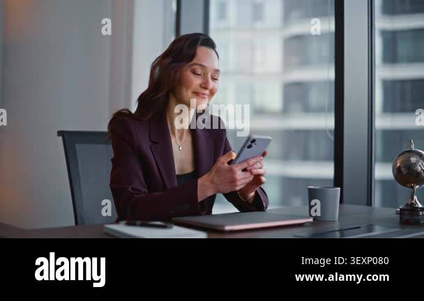 Smiling businesswoman reading sms on mobile phone drinking espresso in ...
