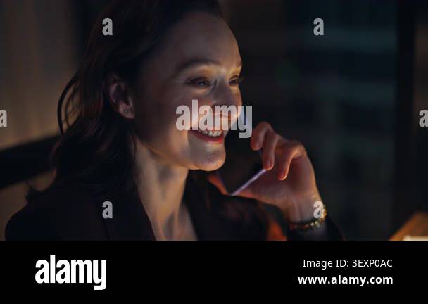 Smiling entrepreneur talking cellphone at night interior closeup ...