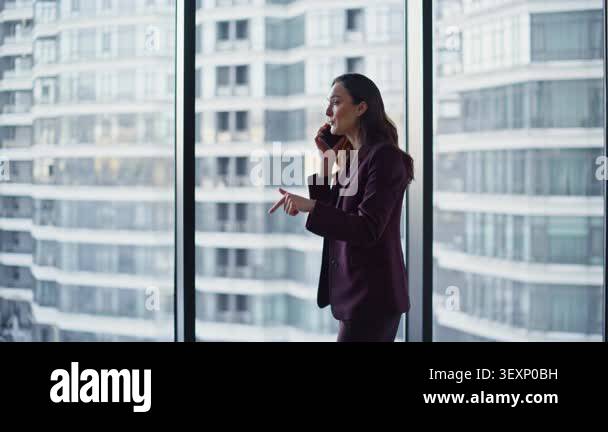 Emotional businesswoman arguing cellphone standing panoramic office ...