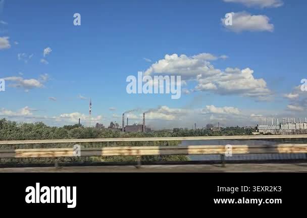 An industrial zone with factory buildings and smoke rising into the sky ...